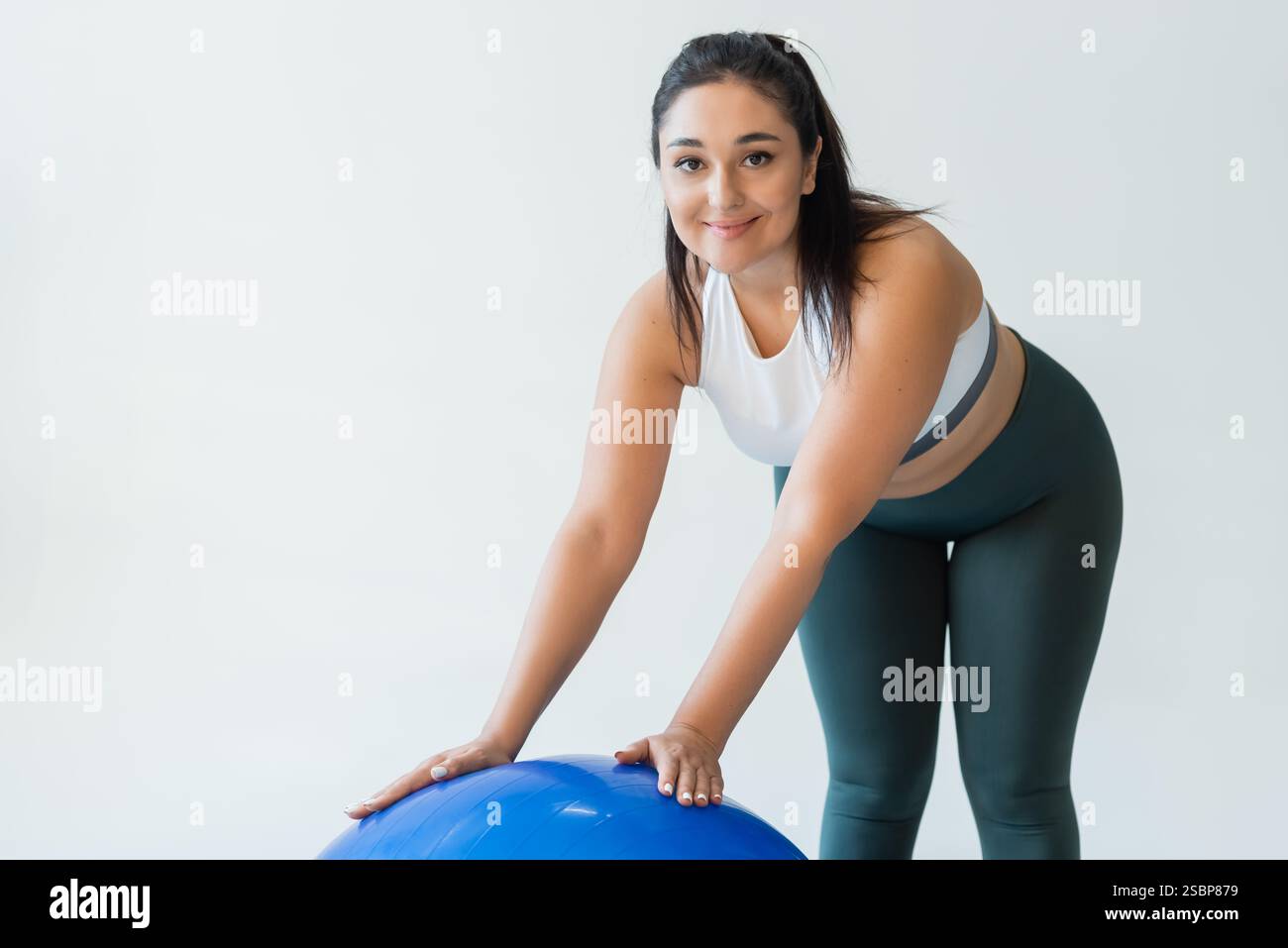 Woman focuses on strength training using a stability ball in a bright ...