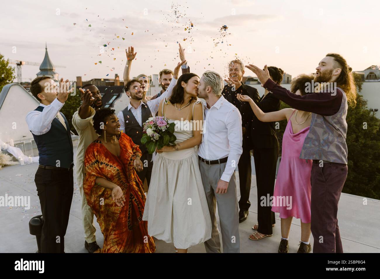 Happy wedding guests throwing confetti on newlywed couple kissing on ...