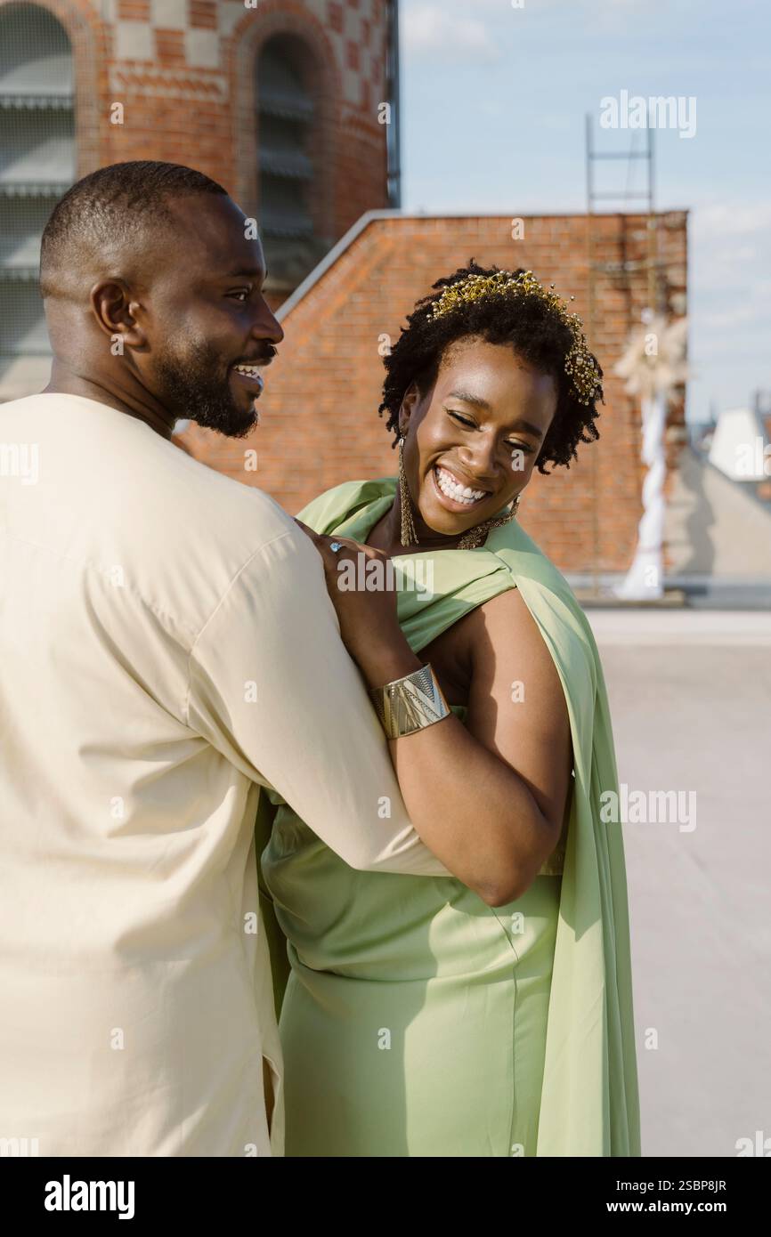 Happy newly married couple laughing while standing on rooftop Stock ...