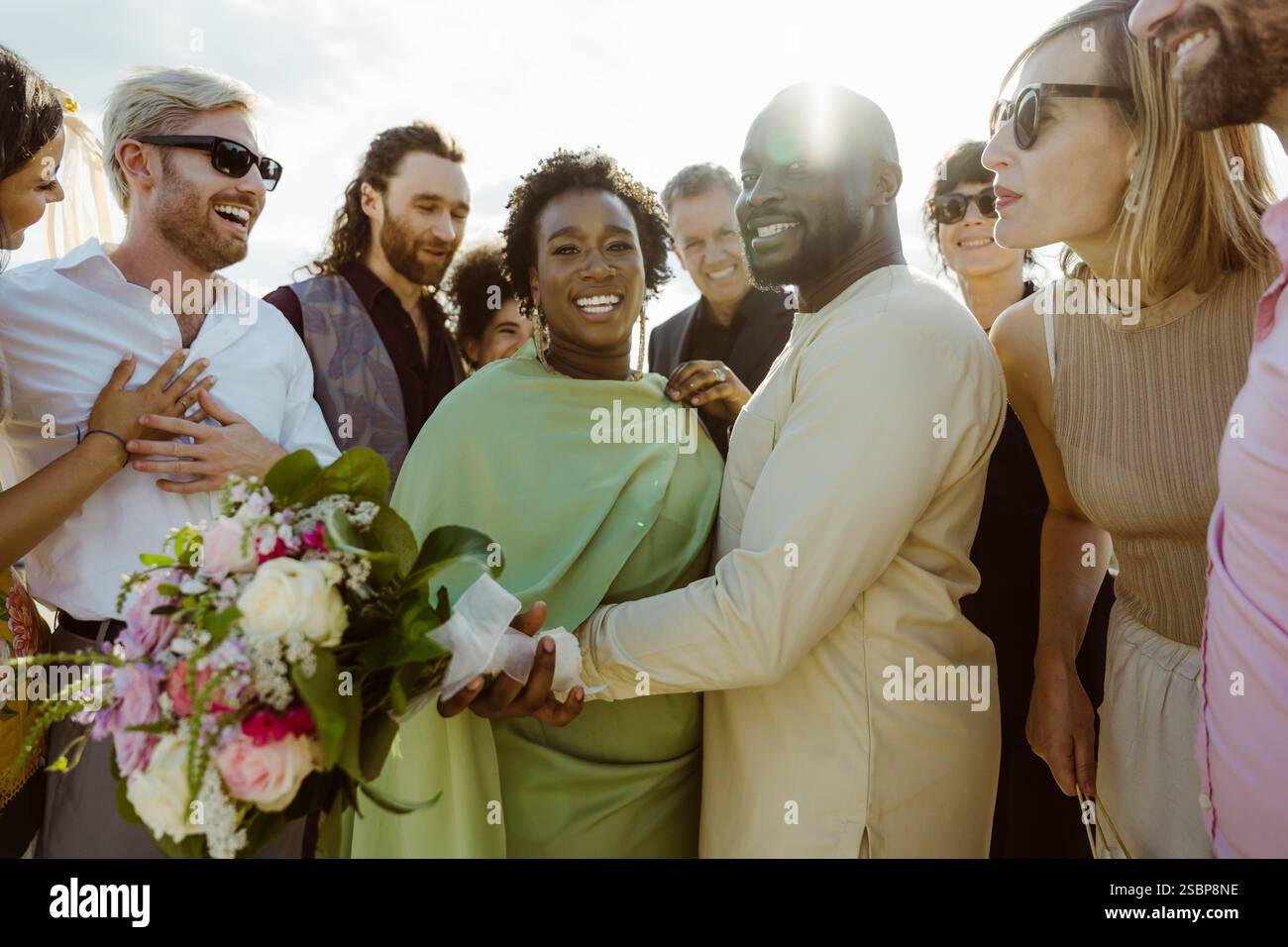 Portrait of happy newly married couple amidst happy guests at wedding ...