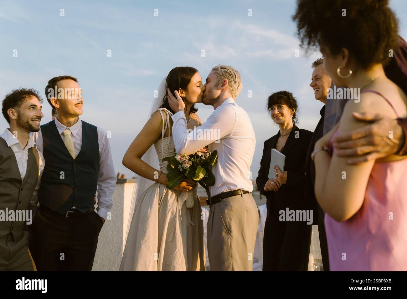 Young married couple kissing each other at wedding ceremony on rooftop ...