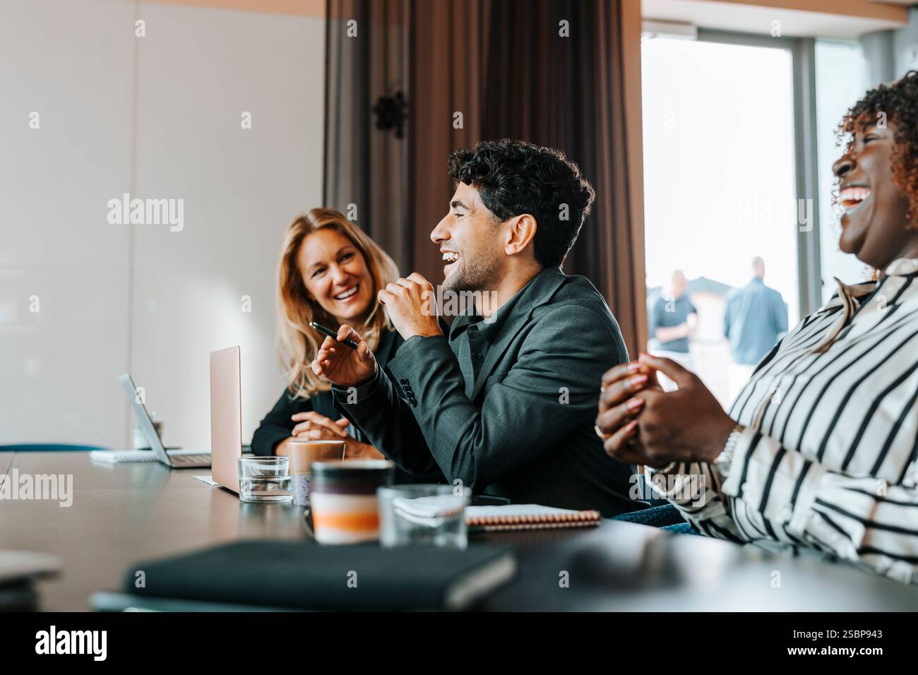 Happy male and female entrepreneurs laughing during business meeting in ...