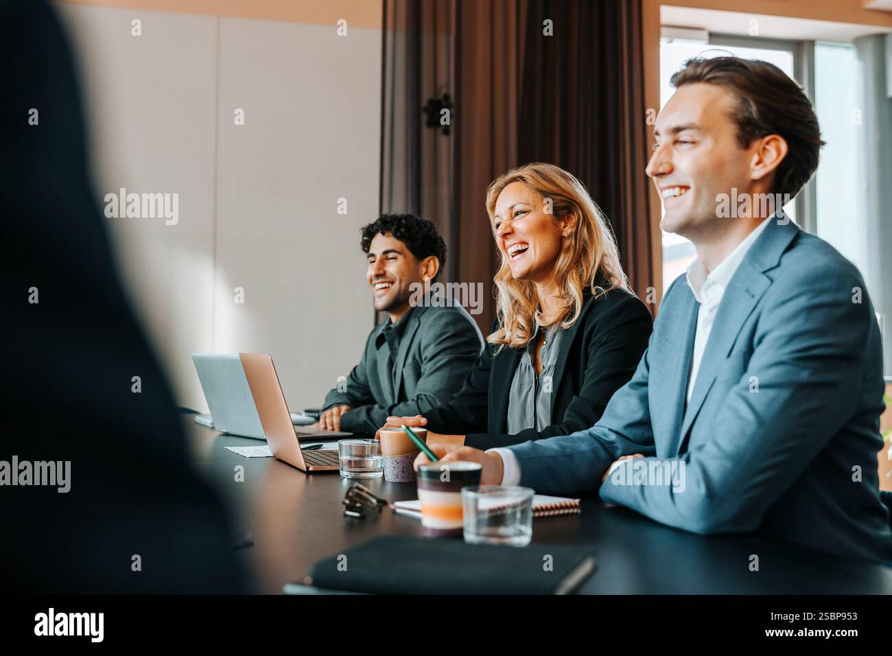 Happy multiracial male and female entrepreneurs laughing during board ...