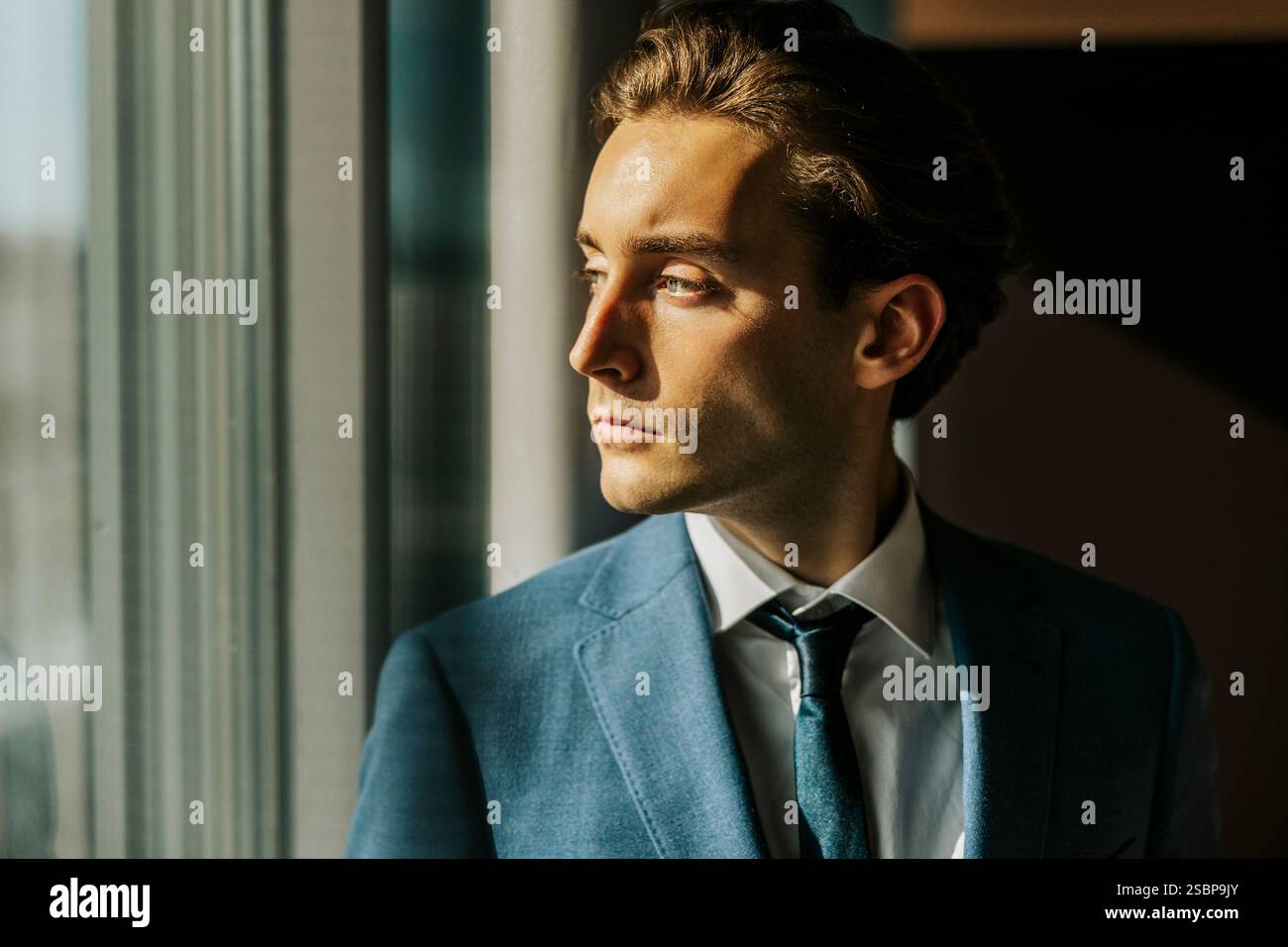 Young male entrepreneur with clean shave face looking through window at ...