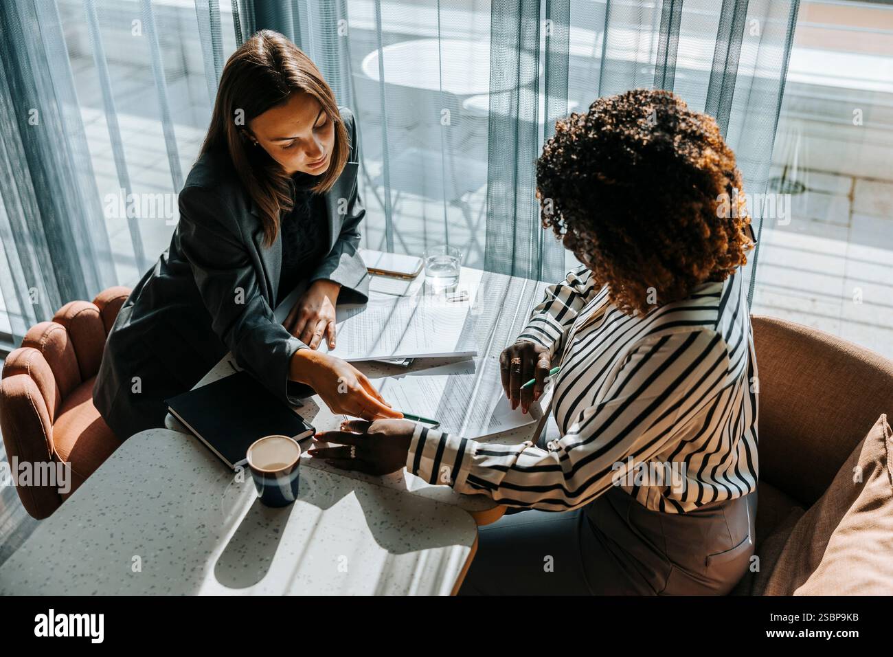 High angle view of female entrepreneur helping client while filling ...