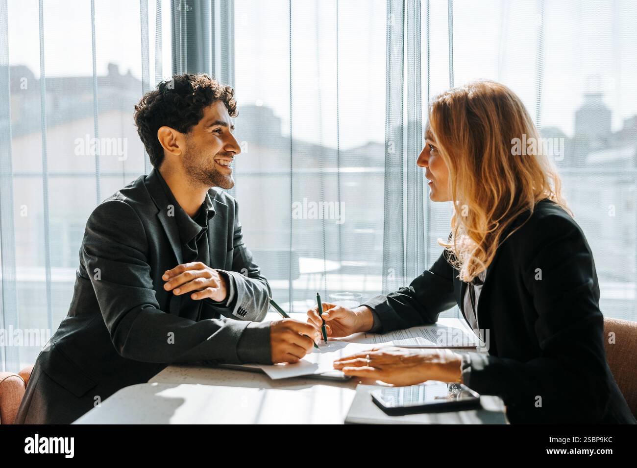 Happy male client talking with female entrepreneur while filling form ...