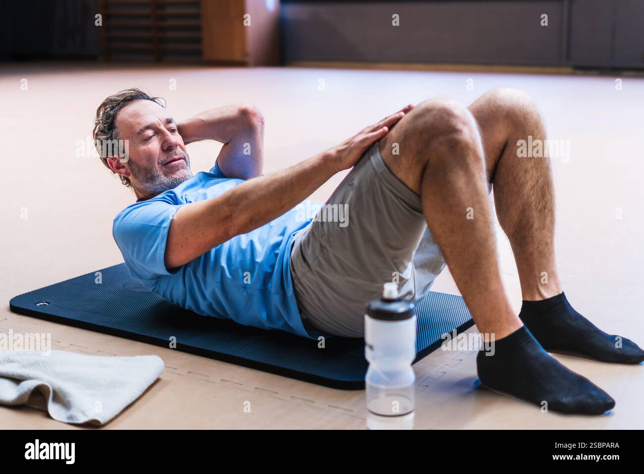 Portrait of a mature man doing sit-ups on a mat at the gym He is ...