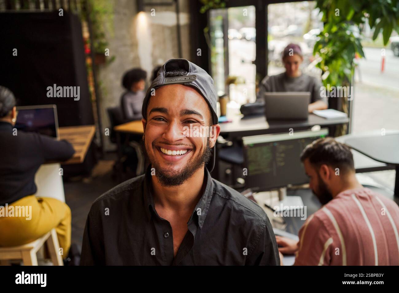 Portrait of happy businessman in cap at tech hub Stock Photo - Alamy