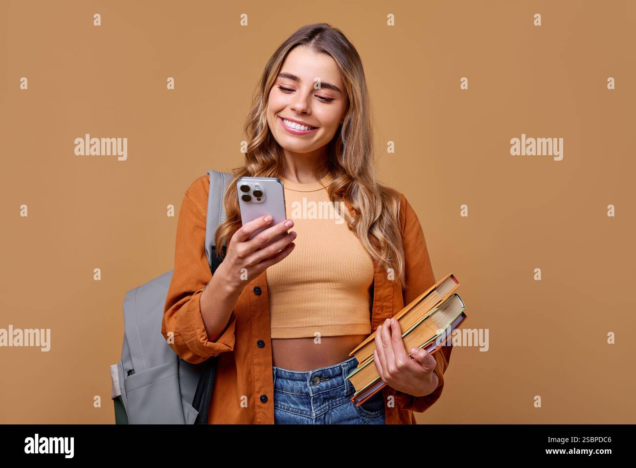A cheerful and happy student enthusiastically holding a stack of books ...