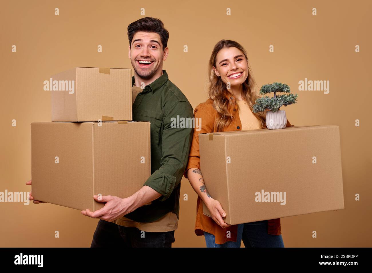 A cheerful young couple is depicted standing backtoback, each holding ...