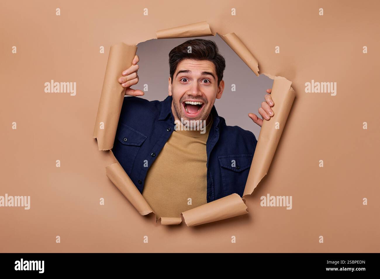 A cheerful man with a beard smiles broadly and gestures playfully while ...
