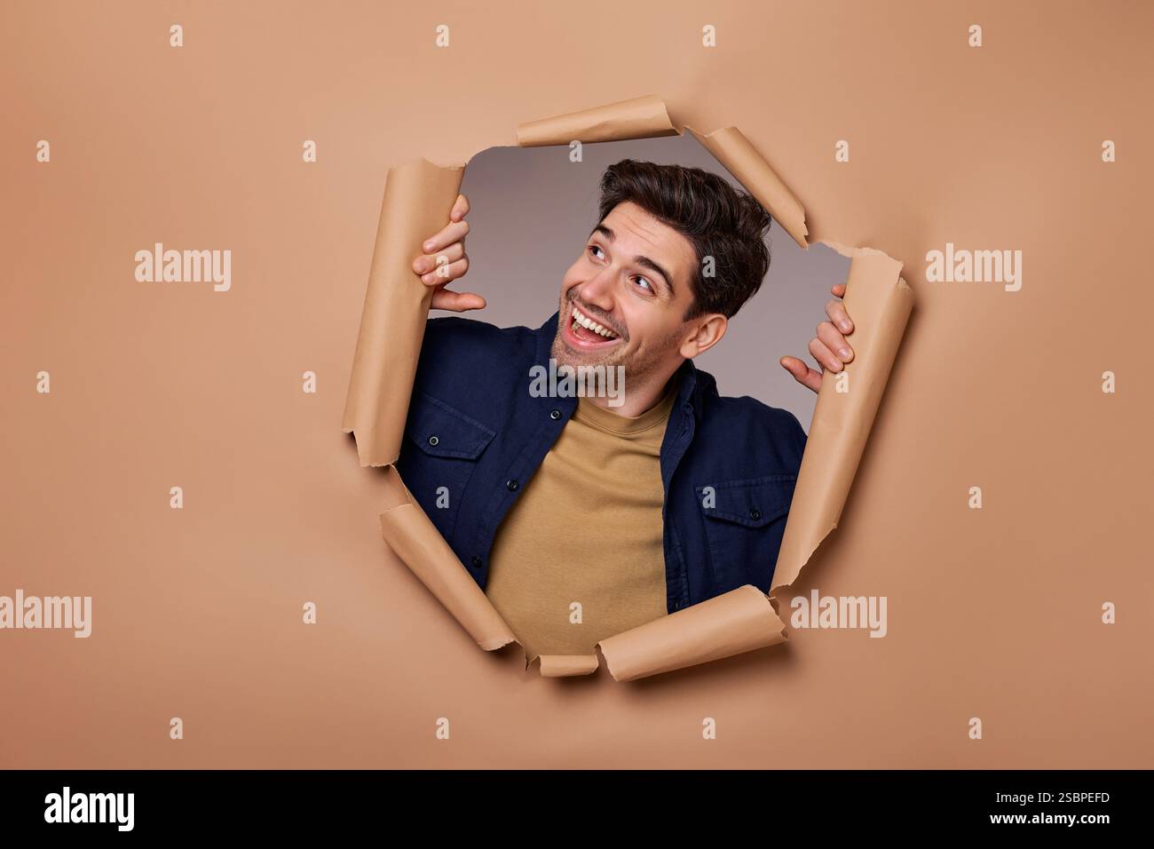 A cheerful man with a beard smiles broadly and gestures playfully while ...