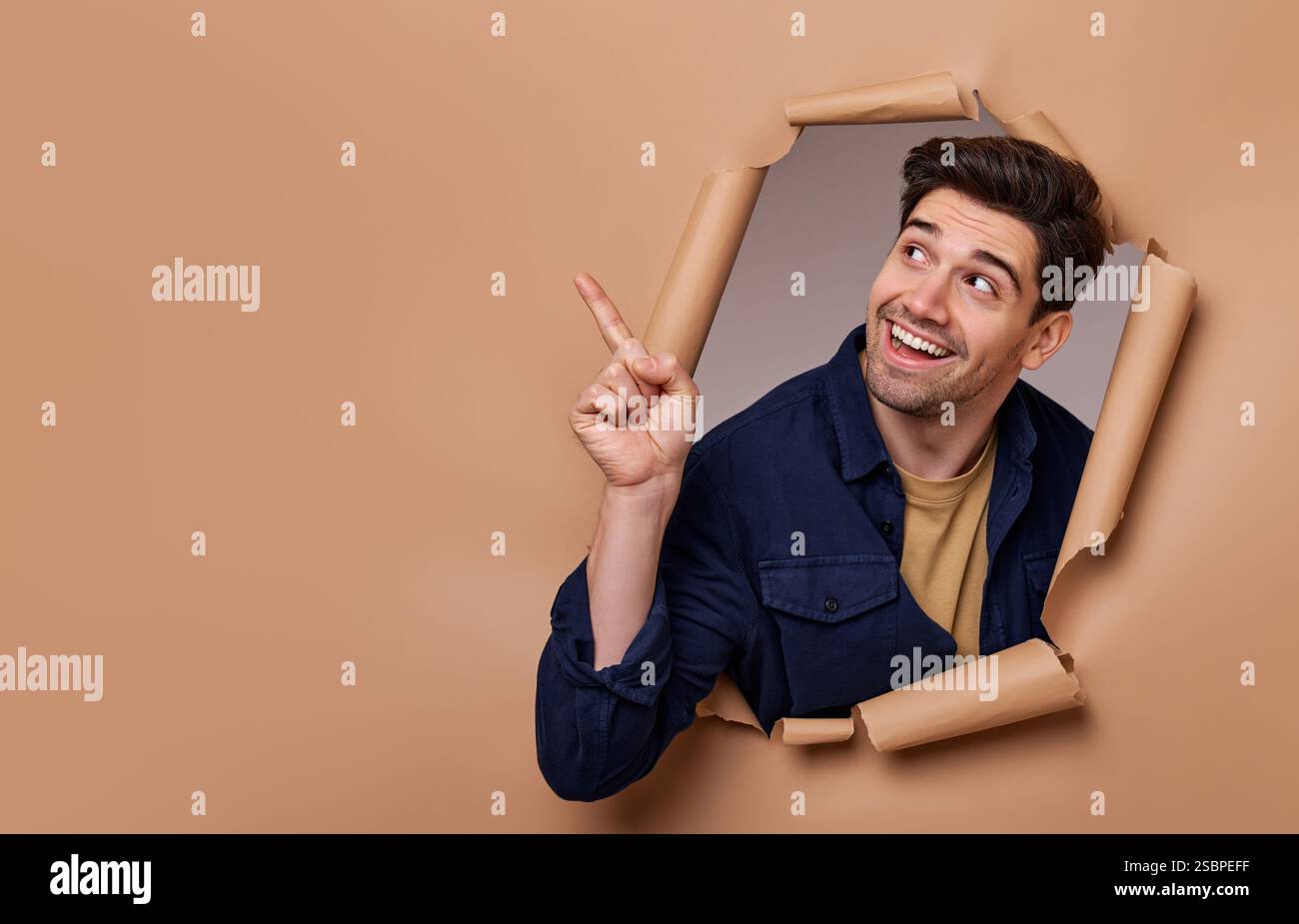 A joyful young man with an infectious smile playfully points while ...