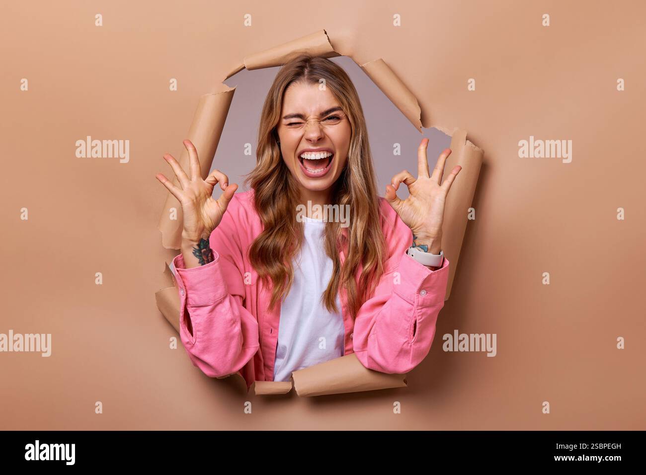 A cheerful and vibrant young woman joyfully breaks through a colorful ...