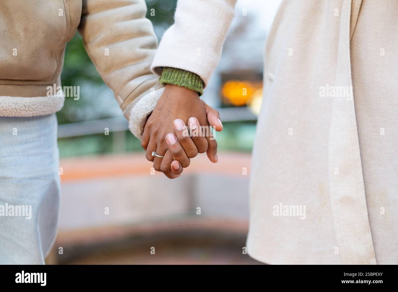 Close up of engaged couple holding hands showing off engagement ring ...