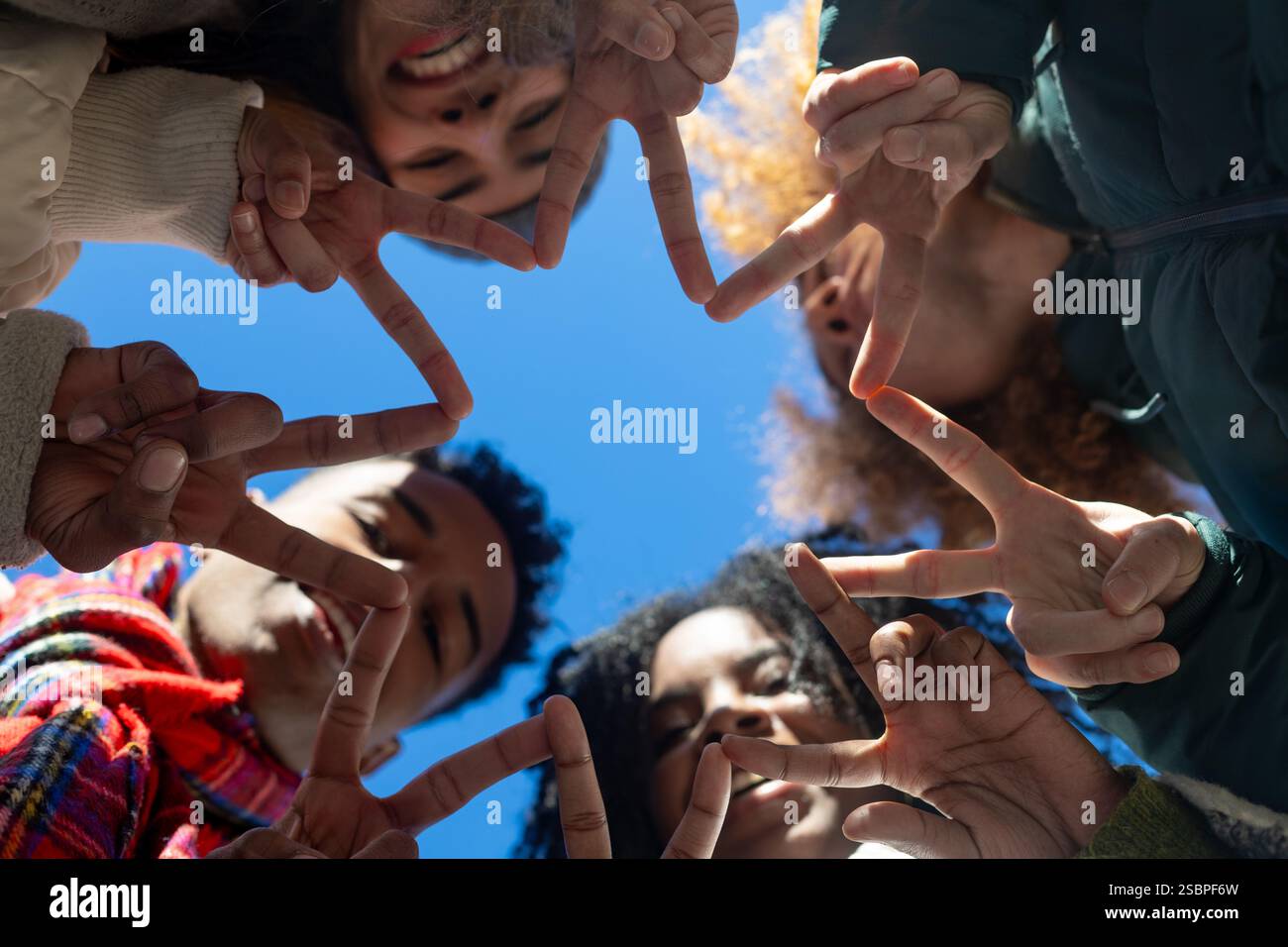 Happy multi ethnic friends forming a star shape with their fingers ...