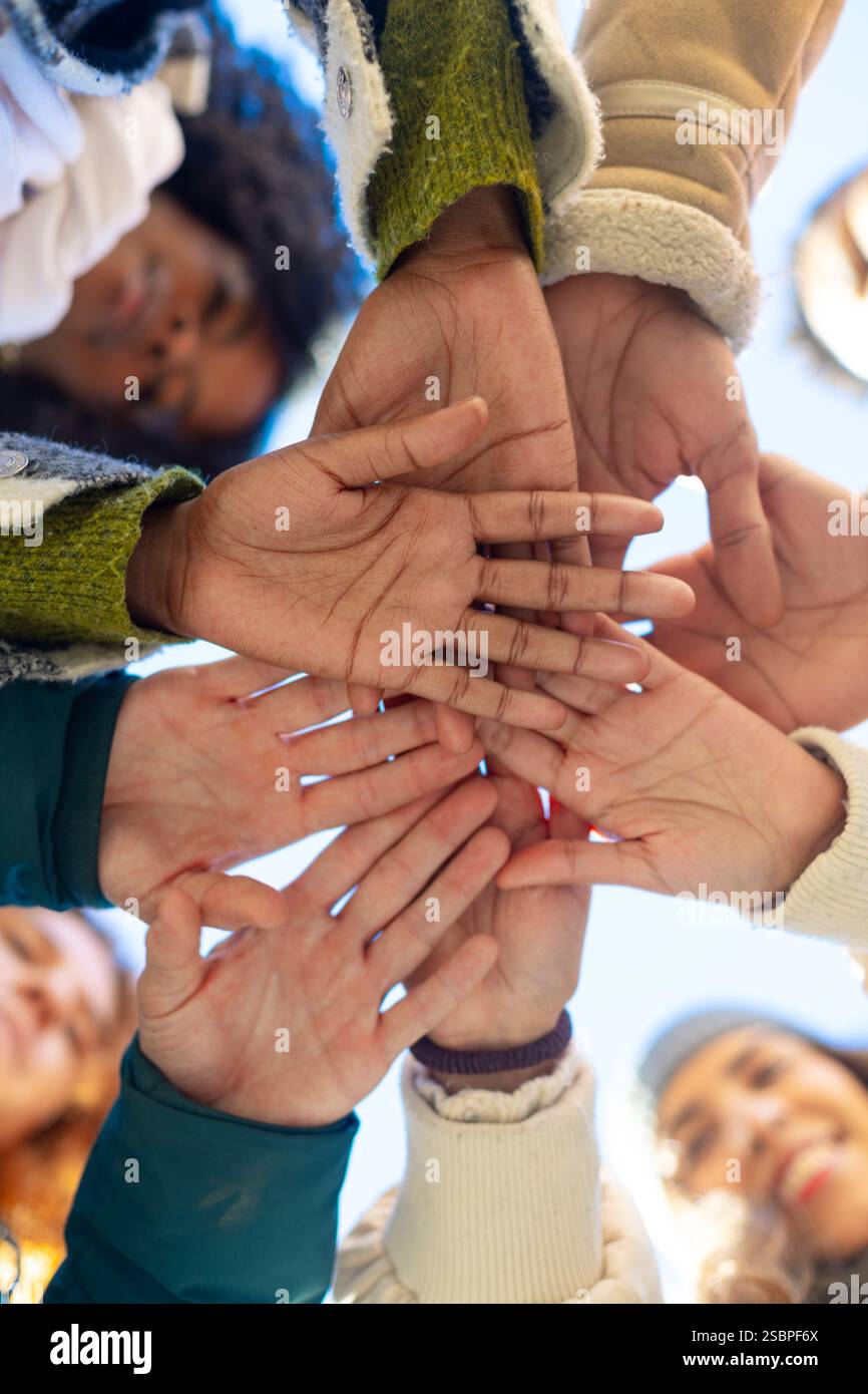 Group of diverse students joining hands in a circle, symbolizing teamwork, collaboration, and ...