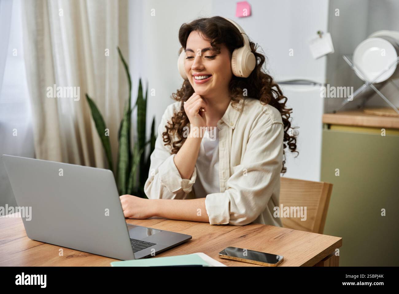 A beautiful young woman smiles while talking on a video call from her ...