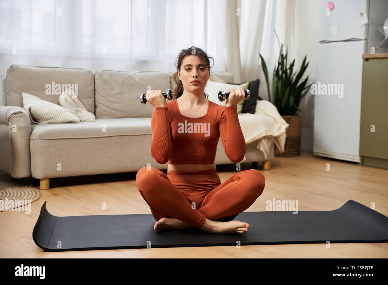A beautiful young woman practices strength training with dumbbells ...