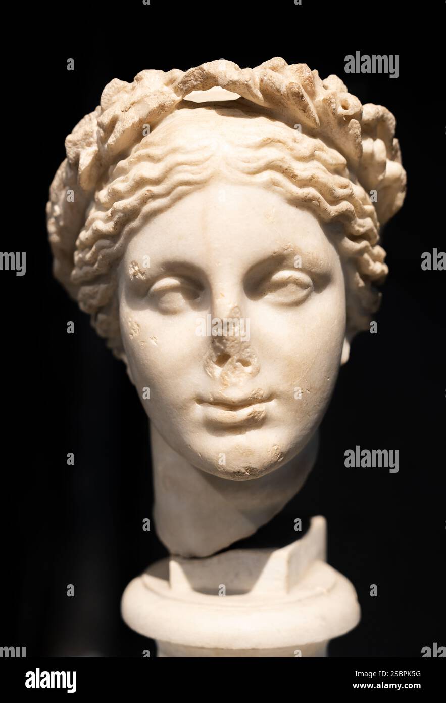 Close-up on ancient marble head in ruins portraiting a smiley roman ...