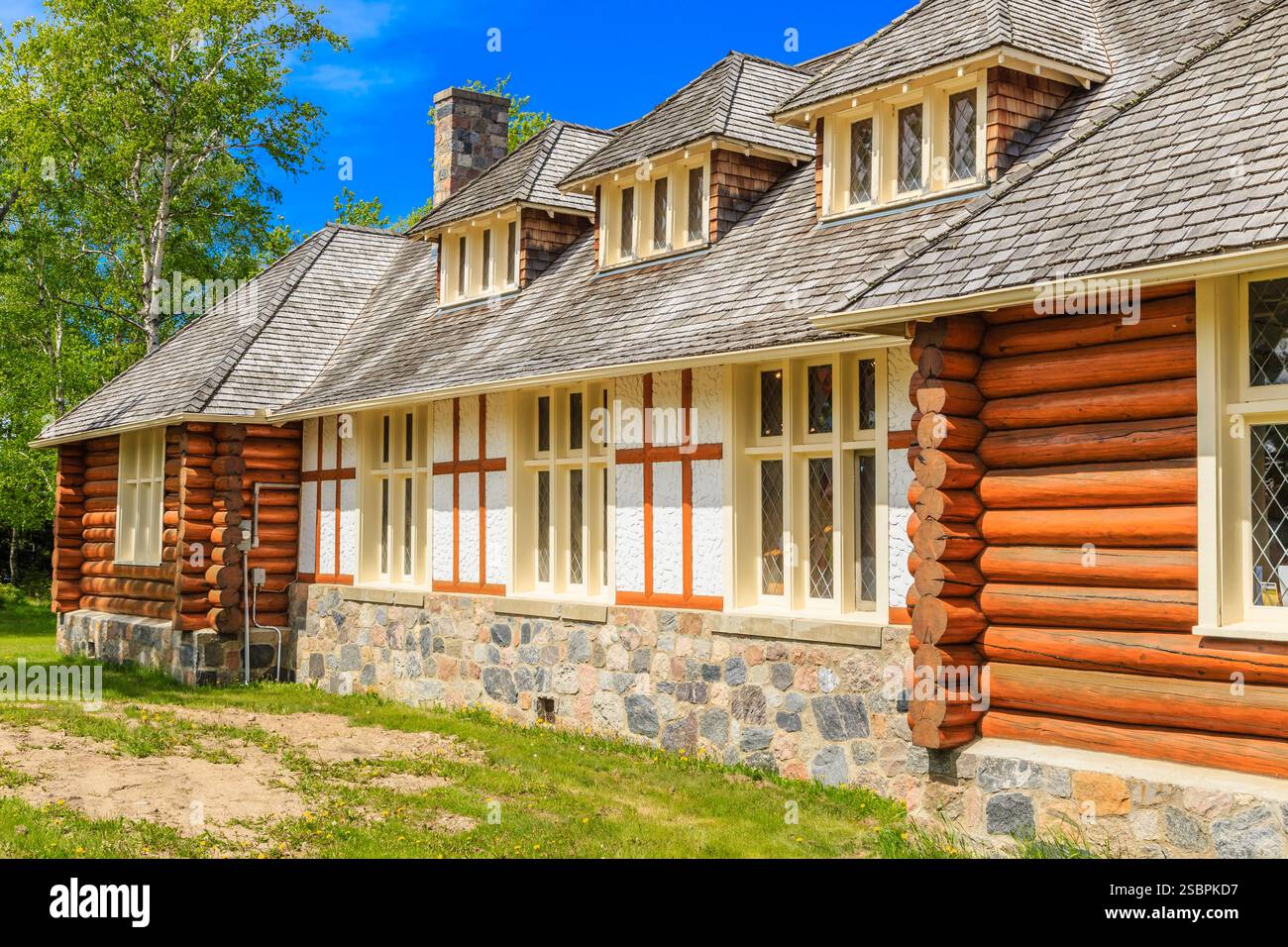 Large log cabin with a white trim. The roof is made of shingles. There ...