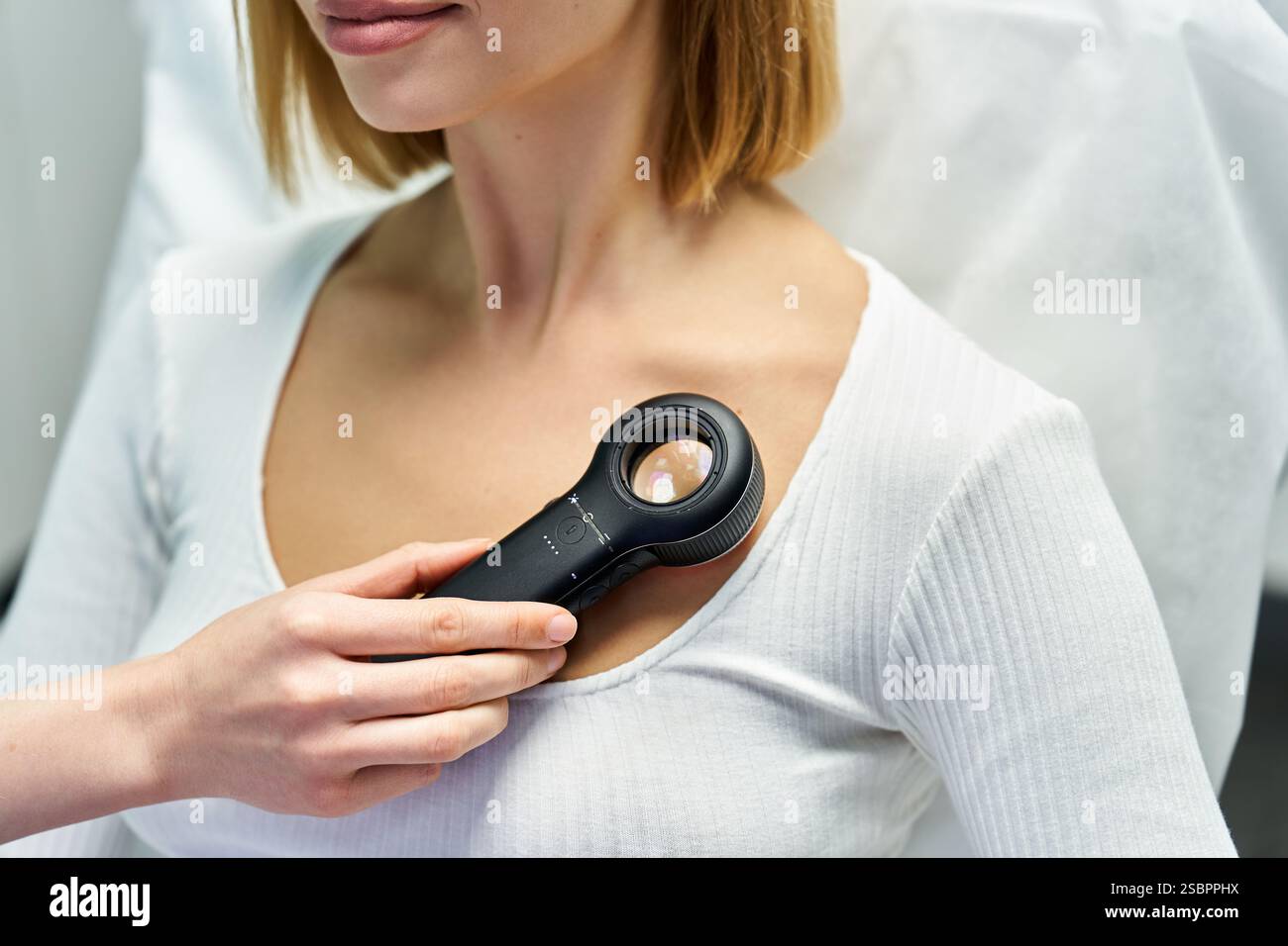 A young woman is receiving a skin examination with a handheld device in ...