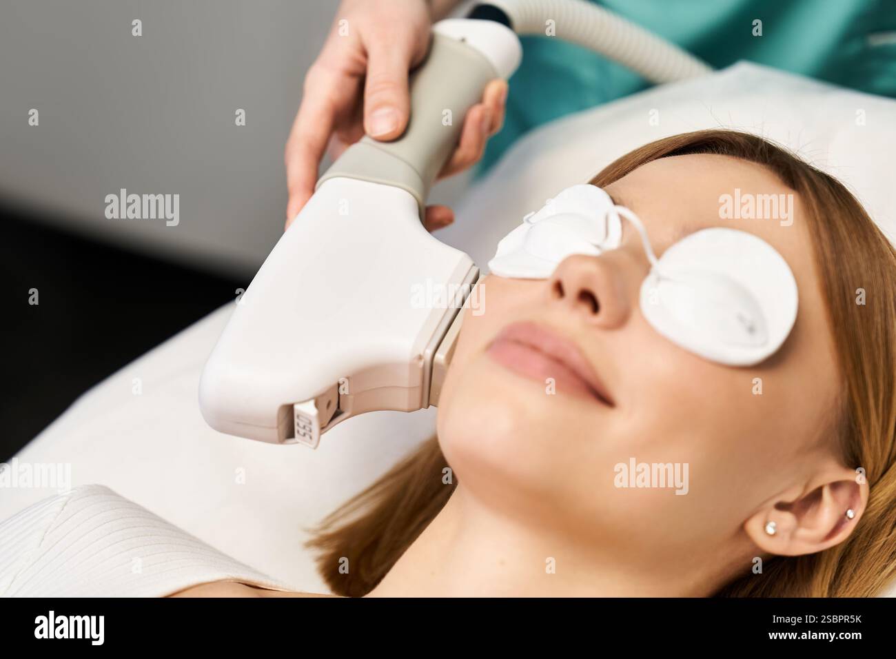 A young person relaxes during a dermatology procedure to improve skin ...