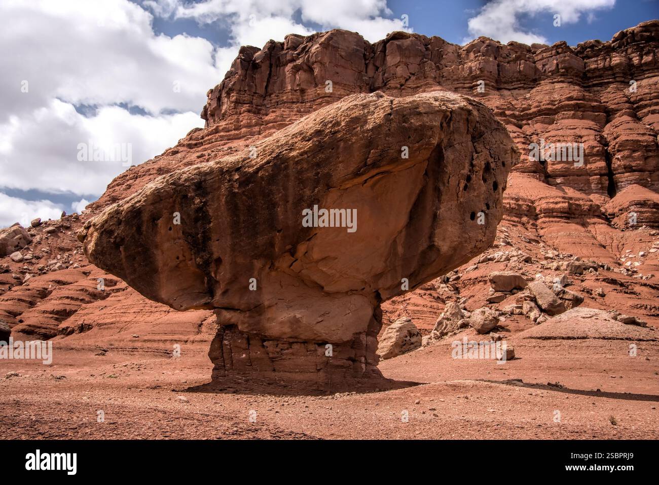 A large rock in the desert. The rock is brown and has a hole in it. The ...