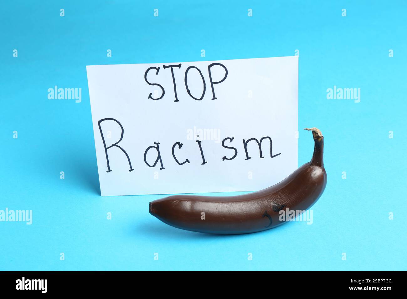 Card with phrase Stop Racism and dark banana with sad face on light ...