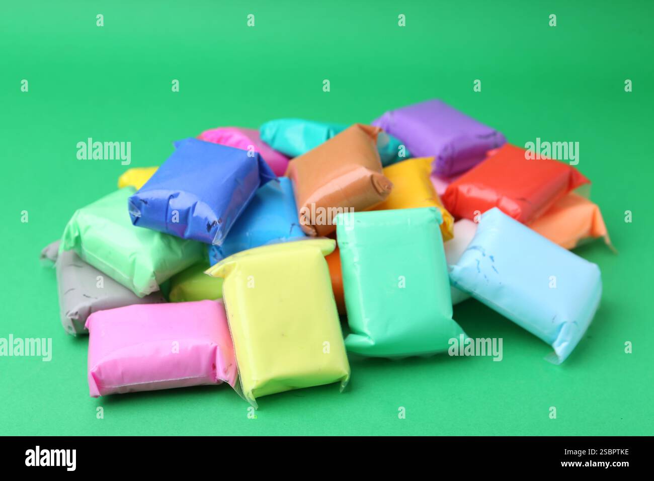 Different colorful play dough in packages on spring green background ...