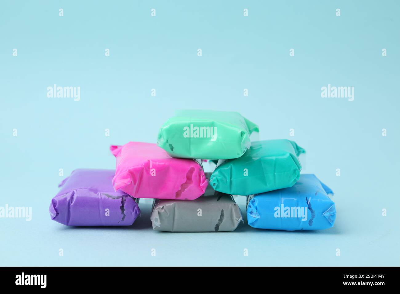 Different colorful play dough in packages on light blue background ...