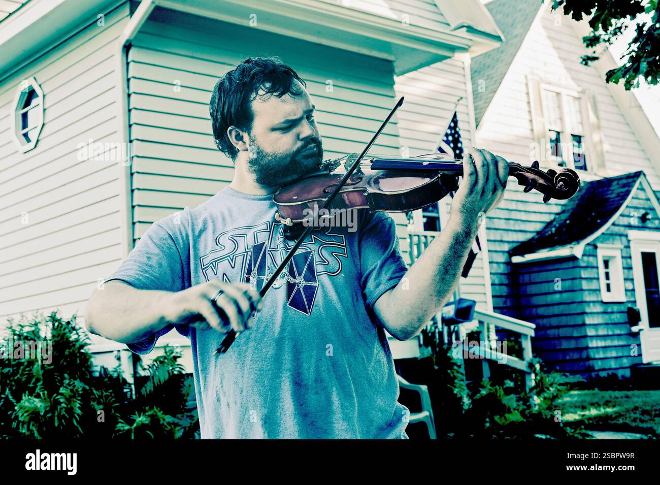 Man playing violin outside in the summer, wearing a star wars t-shirt ...