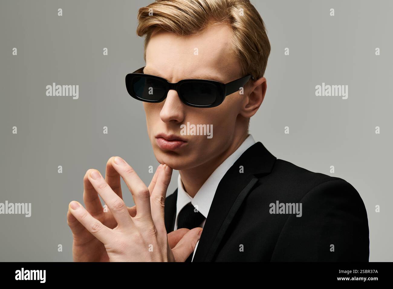 Confident young man in a sleek suit and sunglasses strikes a poised ...