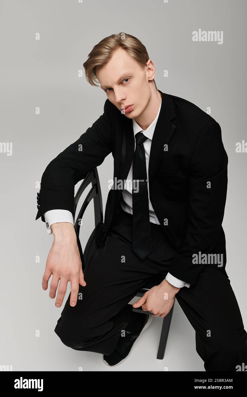 A charming young man exudes confidence while sitting on a chair ...