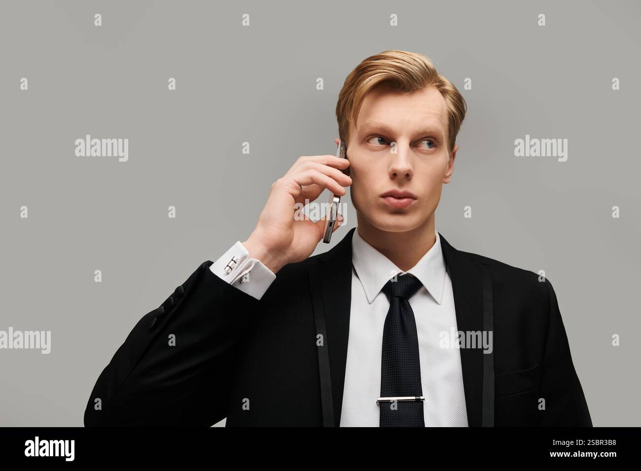 Stylish young man in a suit speaking on his phone with a serious ...