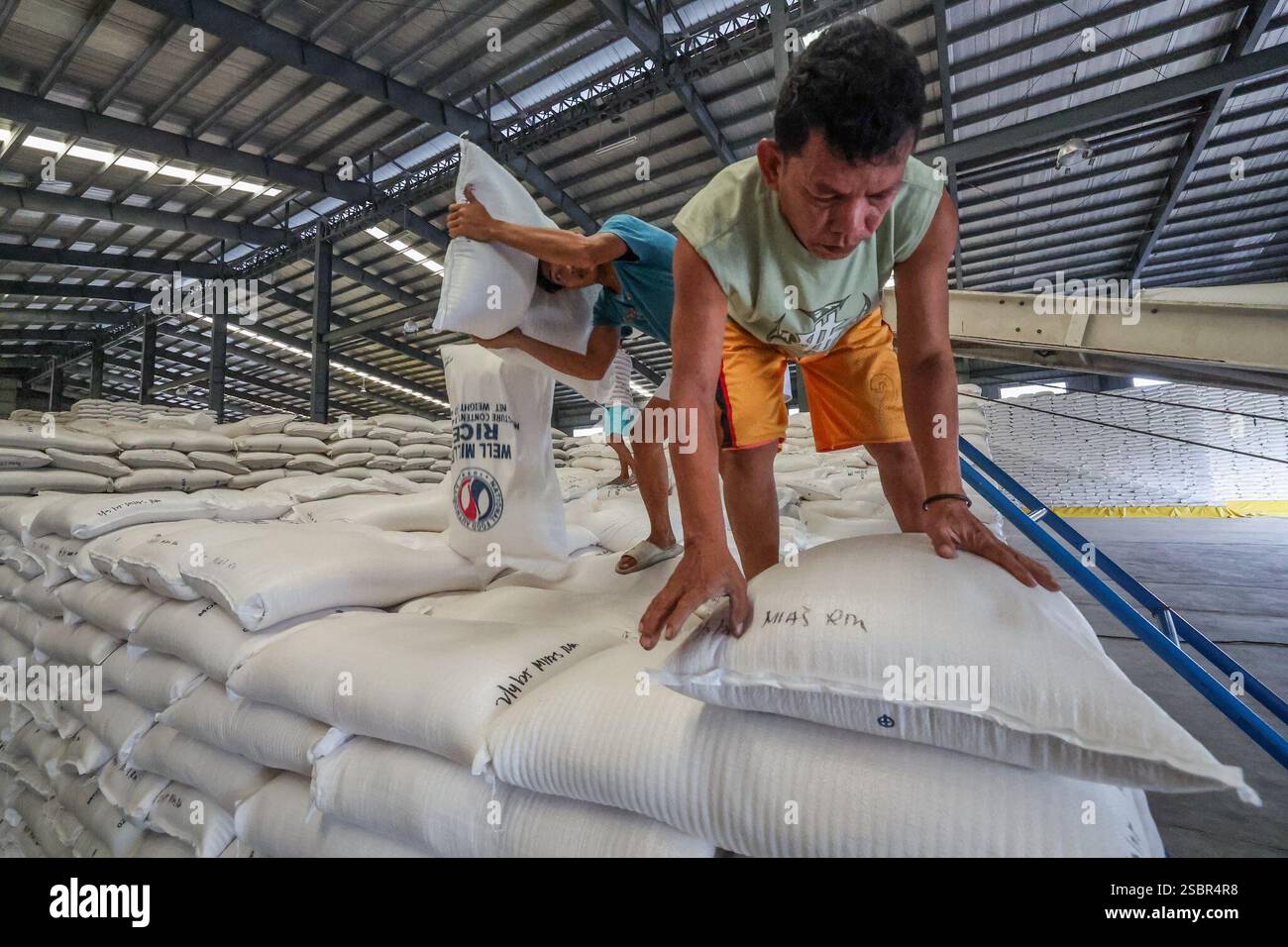 (250204) -- VALENZUELA CITY, Feb. 4, 2025 (Xinhua) -- Workers carry sacks of rice inside the ...