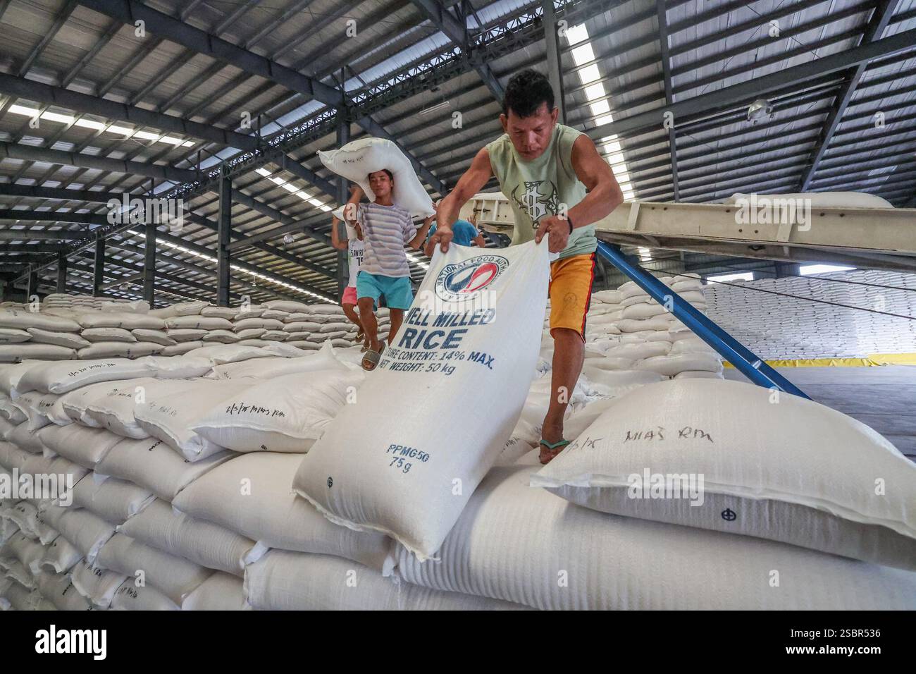(250204) -- VALENZUELA CITY, Feb. 4, 2025 (Xinhua) -- Workers carry sacks of rice inside the ...