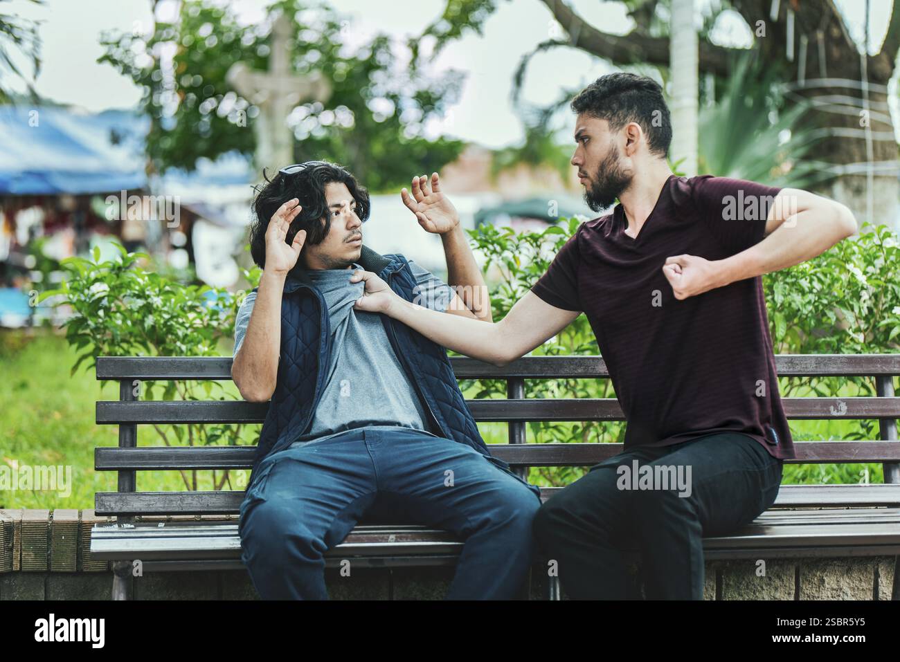 Two male friends arguing on a park bench. Two guys arguing sitting on a ...