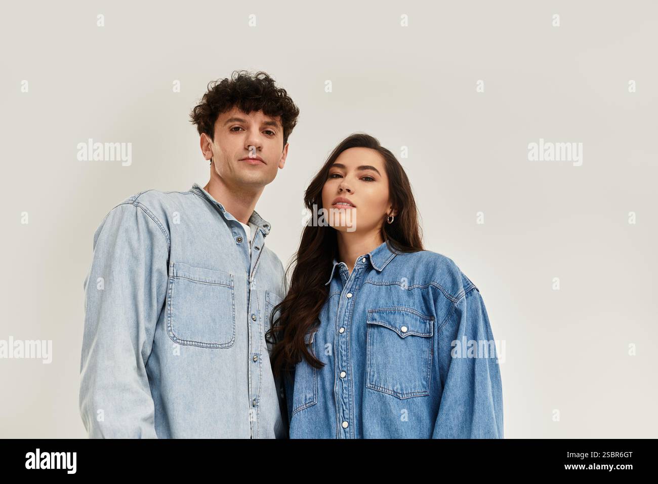 Stylish young duo poses confidently in matching denim outfits against a ...
