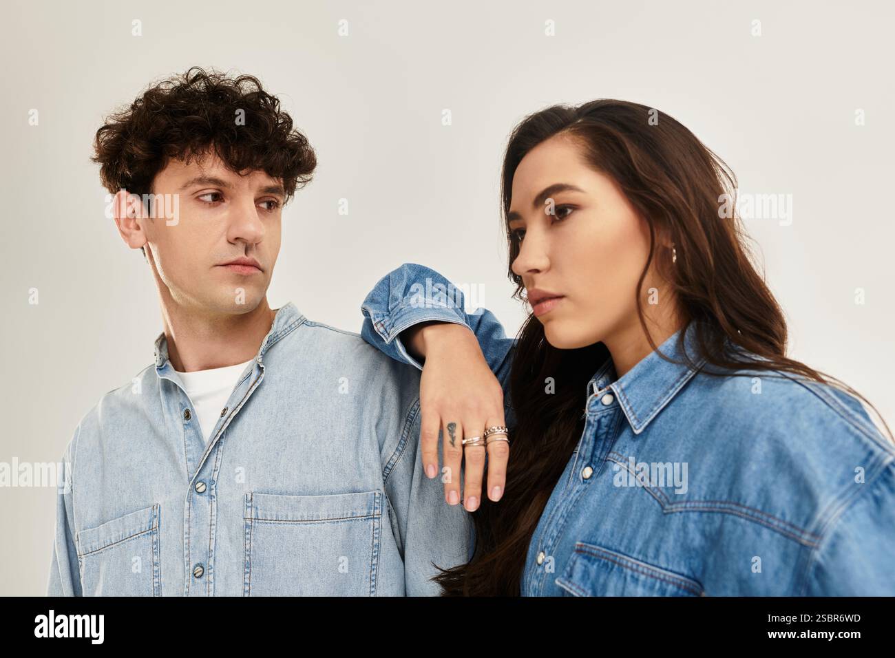 Stylish duo in trendy denim outfits poses against a neutral backdrop ...