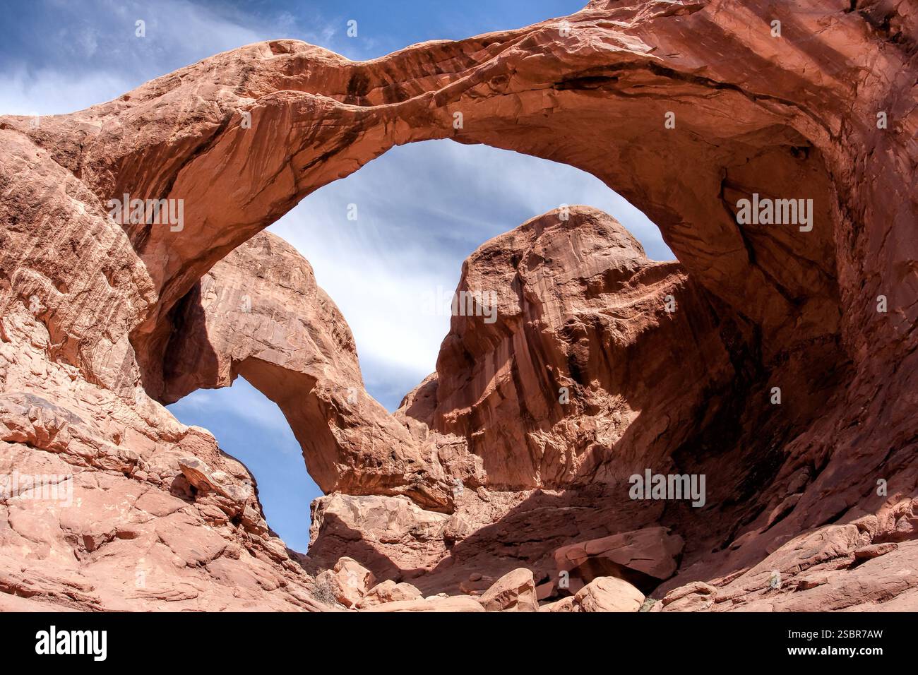 A large archway is in the middle of a desert. The archway is made of ...