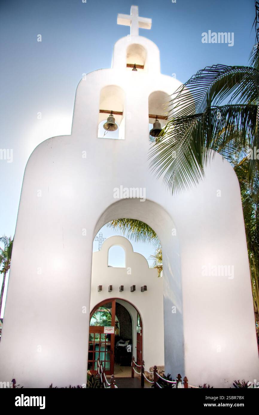 A white church with a bell tower. The bell tower is white and has a ...