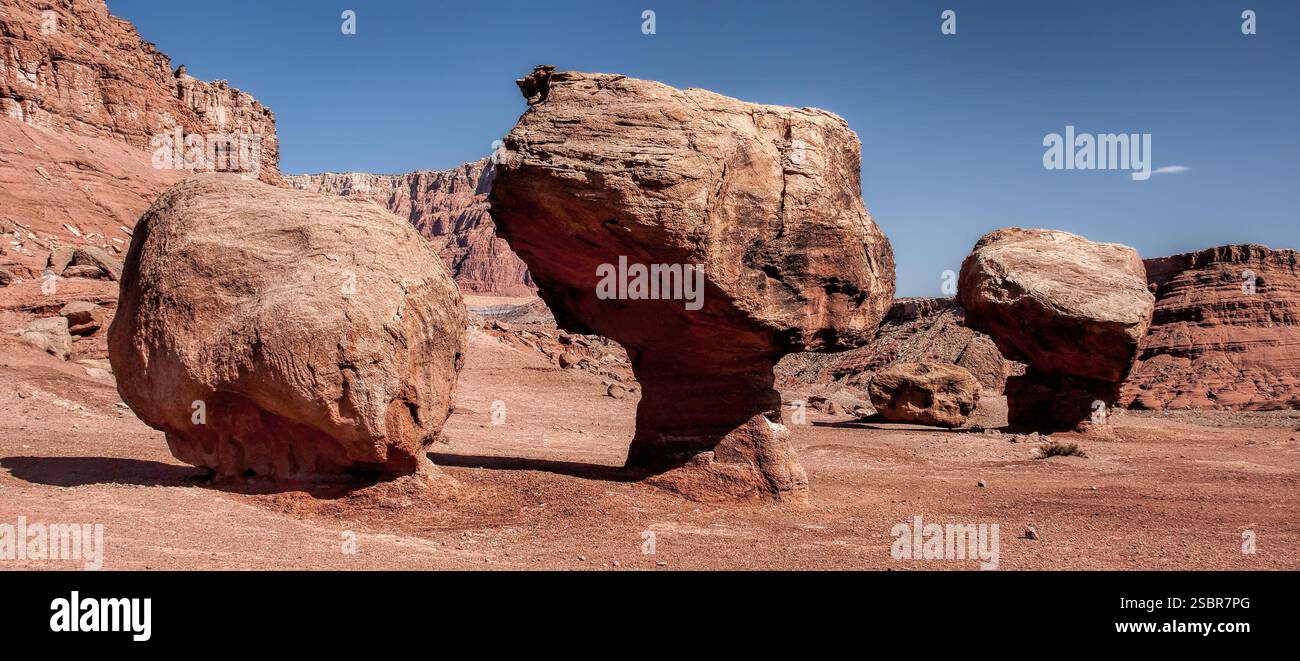 Three large rocks are sitting in a desert. The rocks are brown and are ...