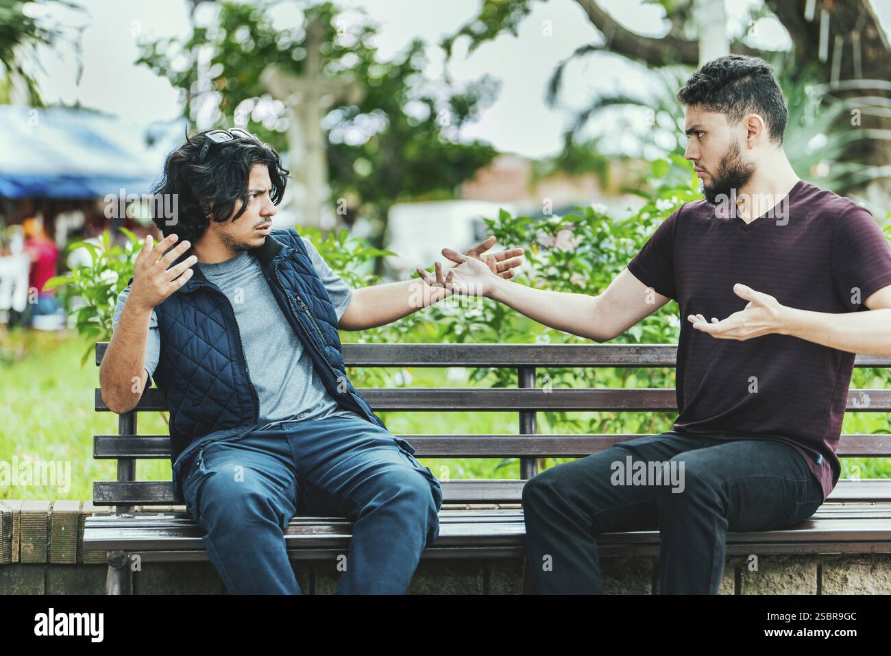 Two people arguing on a park bench. Two guys arguing sitting on a bench ...