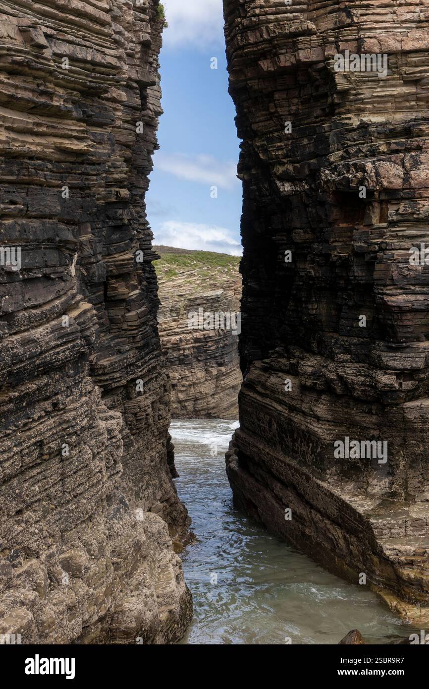 Dramatic rocky cliffs forming a narrow passage with ocean water below ...