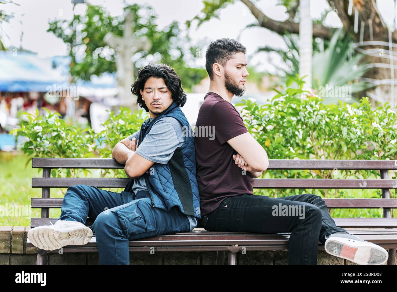 Two angry friends sitting on a park bench. Two friends arguing on a ...
