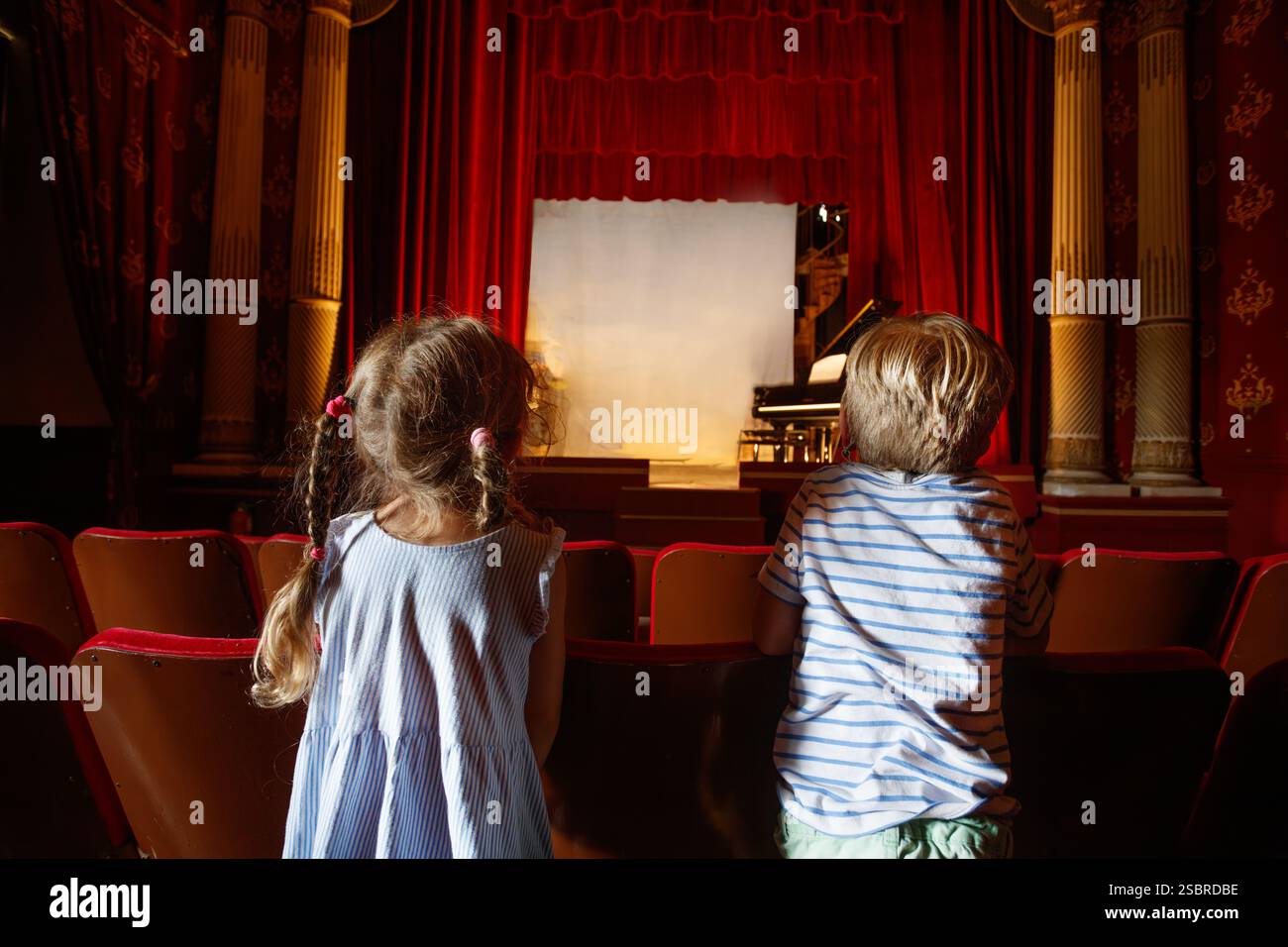 Kids eagerly looking at a stage with piano, waiting for show Stock ...