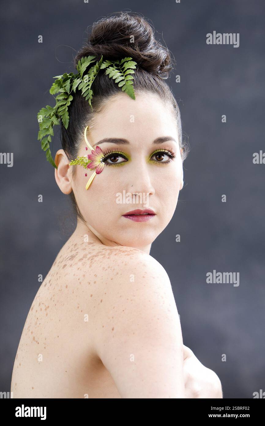 Beautiful brunette face with pink green yellow eye flower petal makeup ...