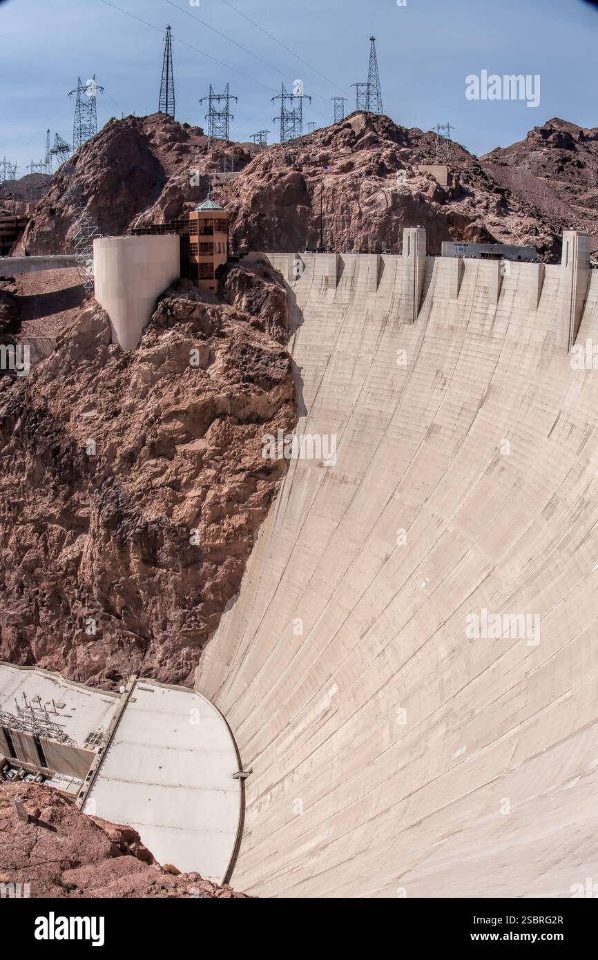 A large dam is built on a mountain. The dam is white and is surrounded ...