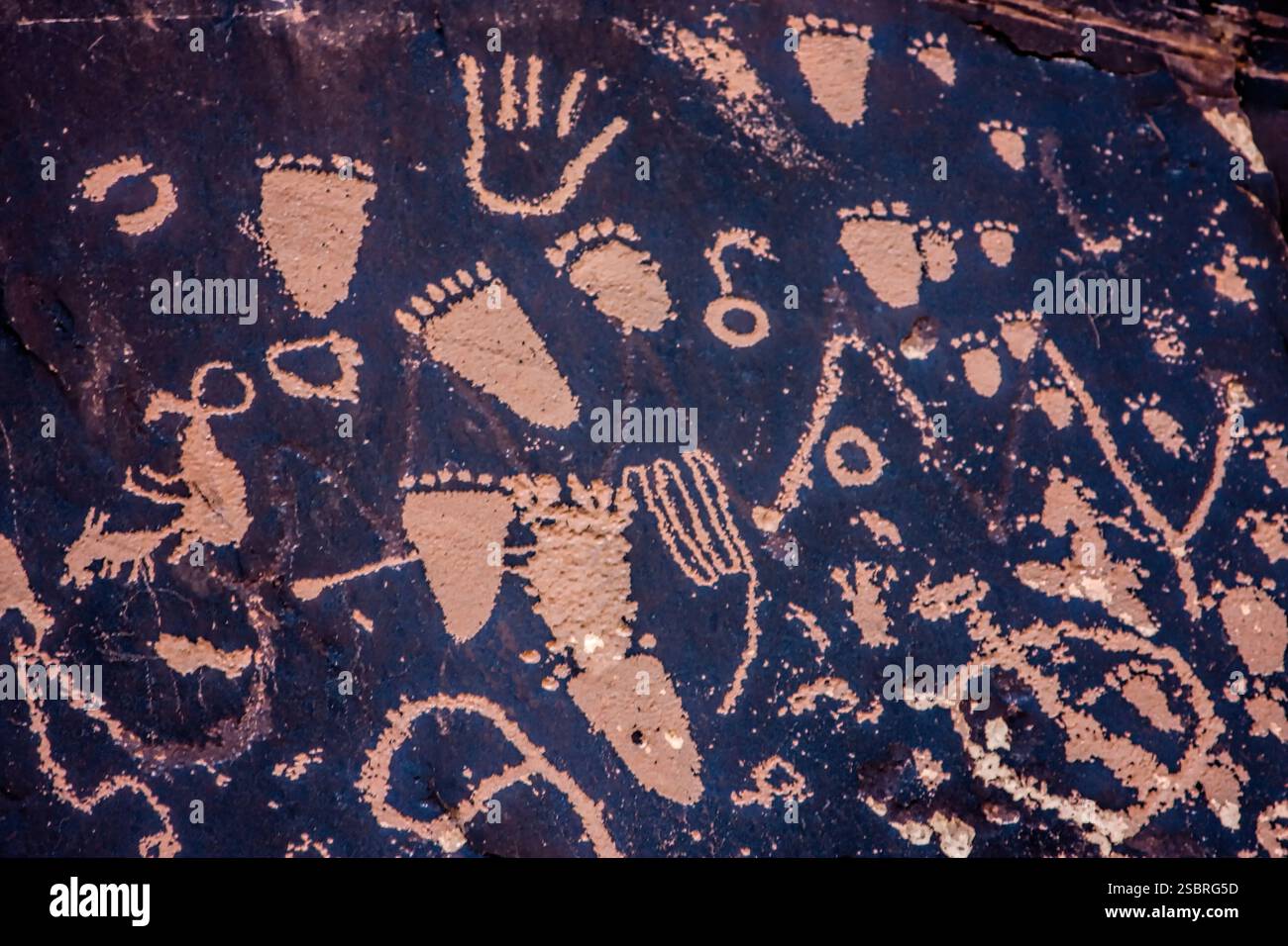 A rock with drawings of feet and other things on it. The feet are in ...